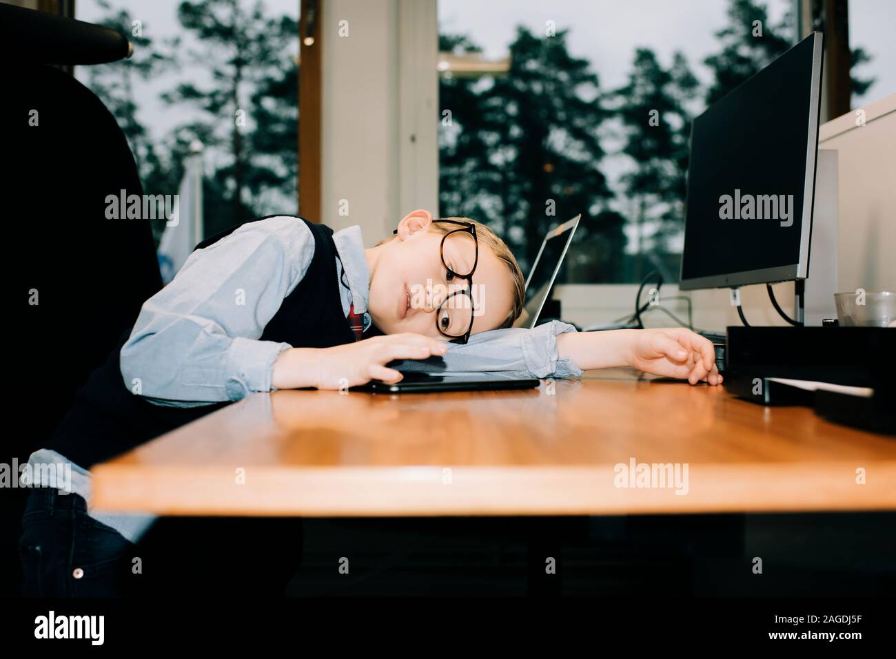 young boy looking tired helping his dad at work in the office Stock ...