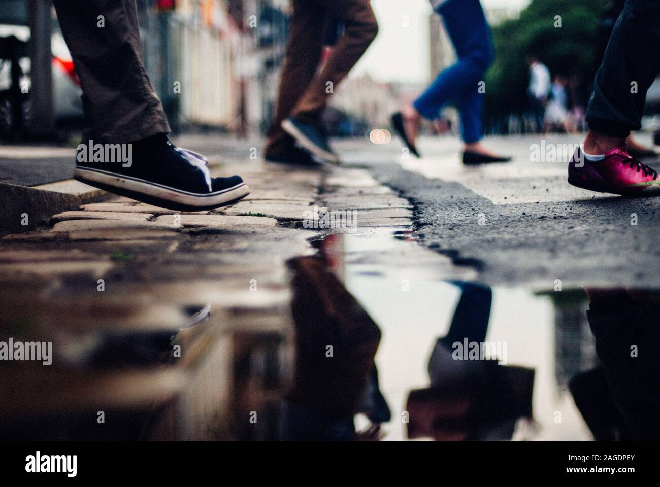 Puddle with the reflection of a group of people crossing the street ...