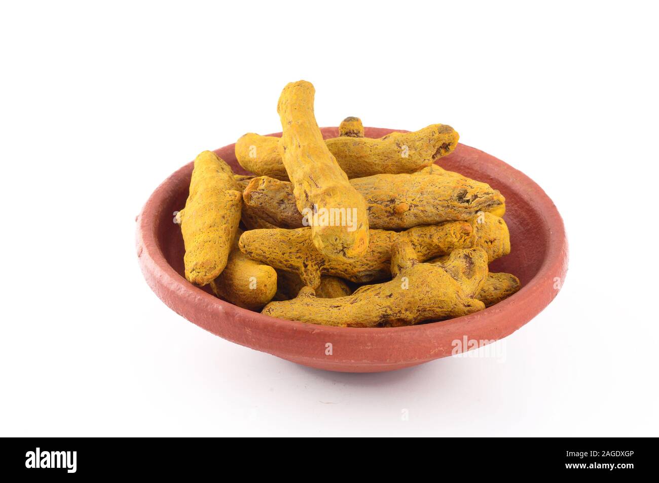 Dry Turmeric roots or barks in clay pot isolated on white background ...