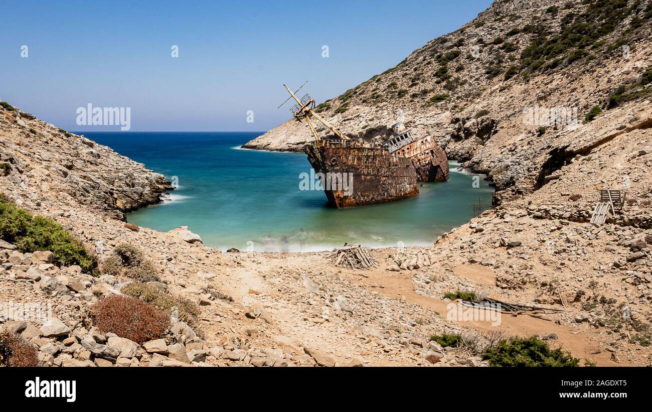 Abandoned rusty ship in the sea near huge rock formations under the ...
