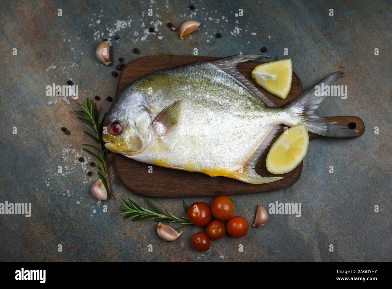 Fresh pomfret fish with herbs spices rosemary tomato and lemon on ...