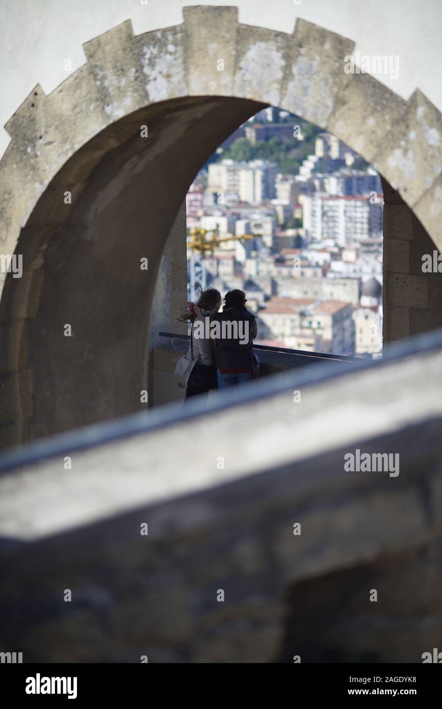 Vertical picture of two people under a stone arch with a view of a ...