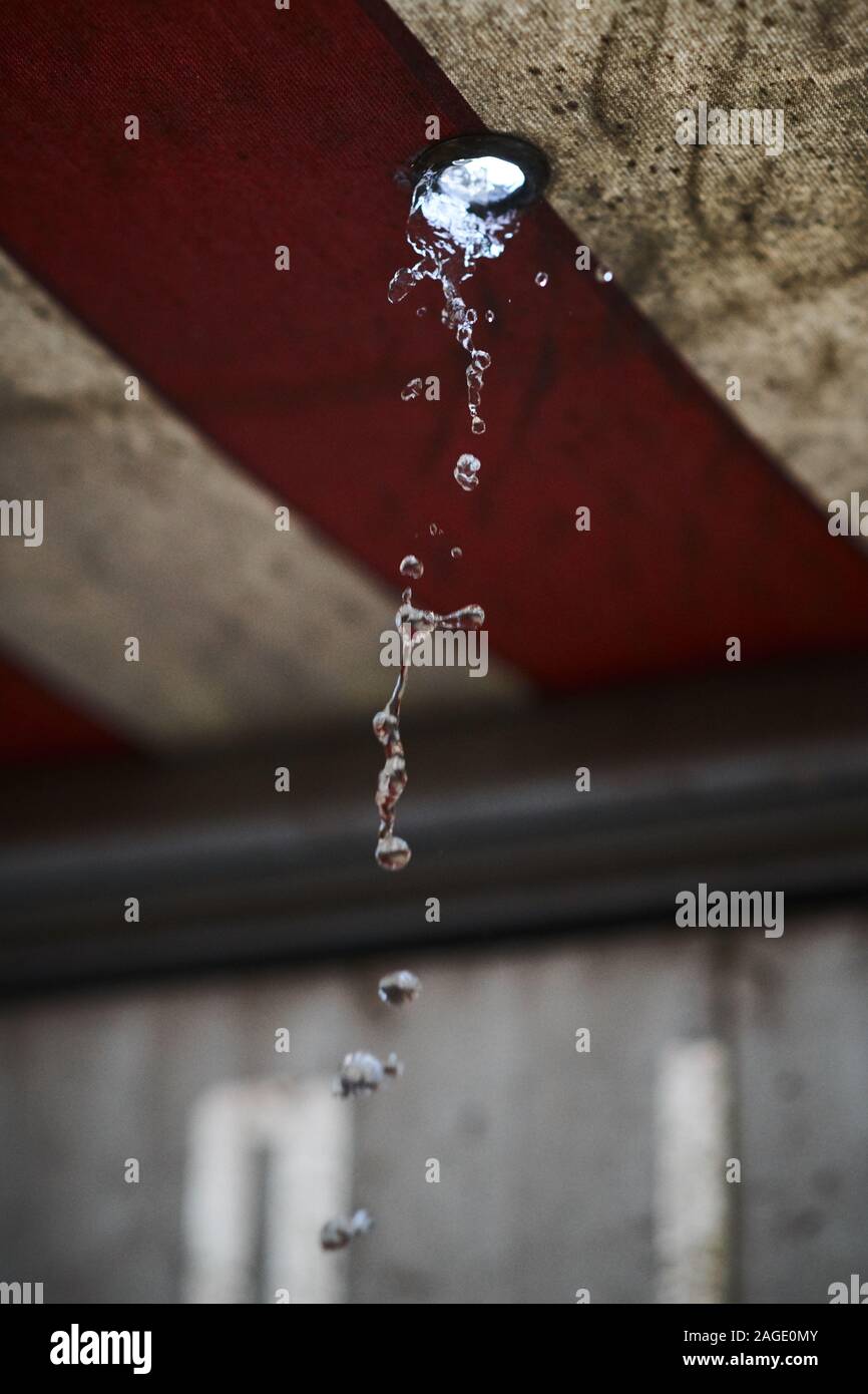 Picture of water drops falling from a red roof with a blurry background ...