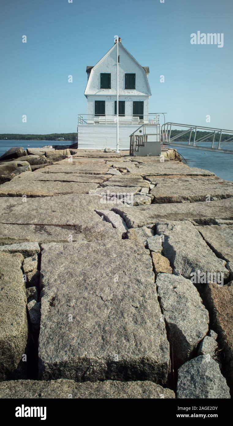 Vertical shot of a white wooden cottage on the rocky pier by the ocean ...