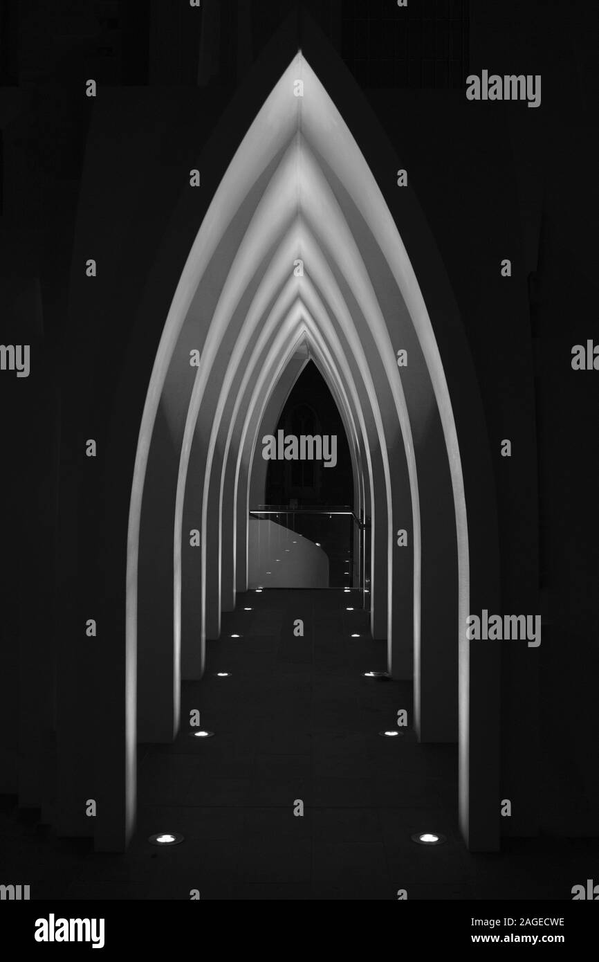 Vertical grey scale shot of an arch shaped hallway in a modern building ...