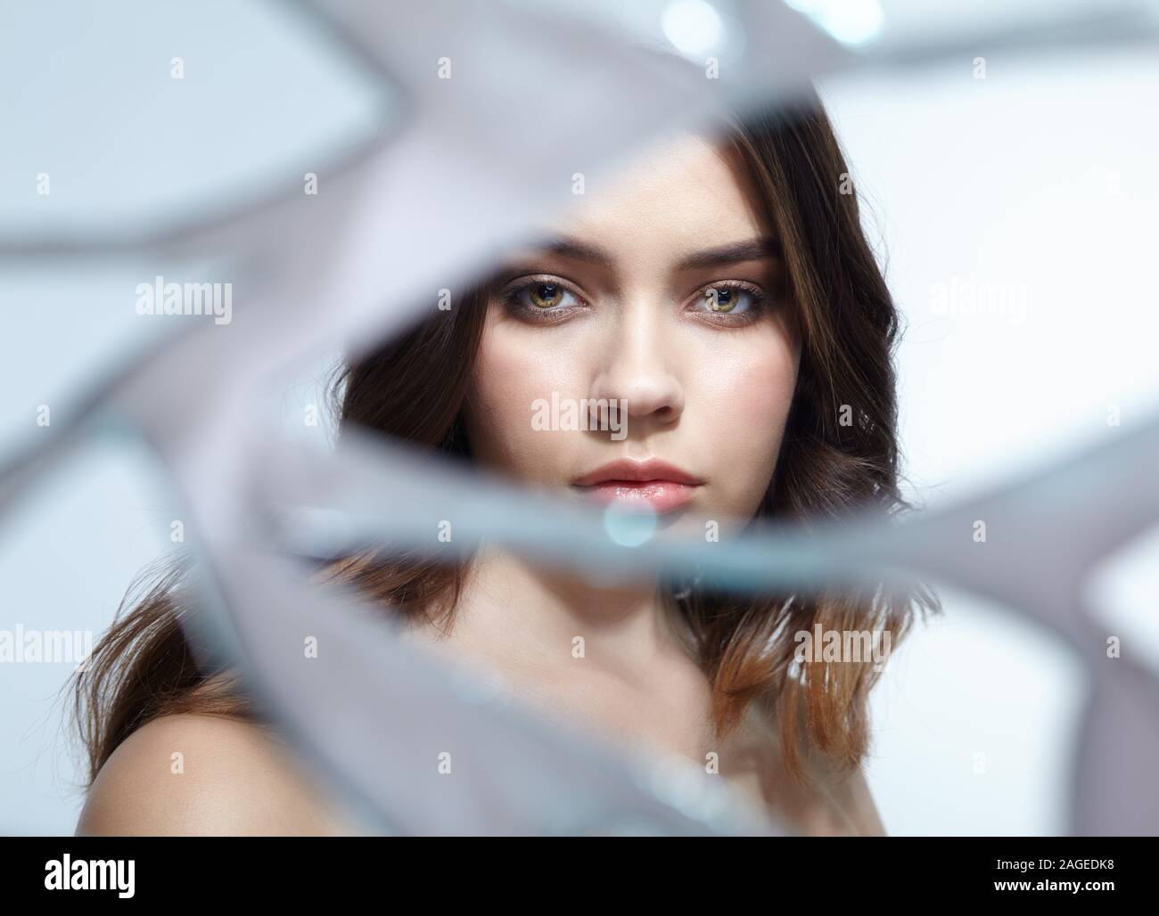 Young woman looks in a broken mirror. Portrait of beautiful female in ...