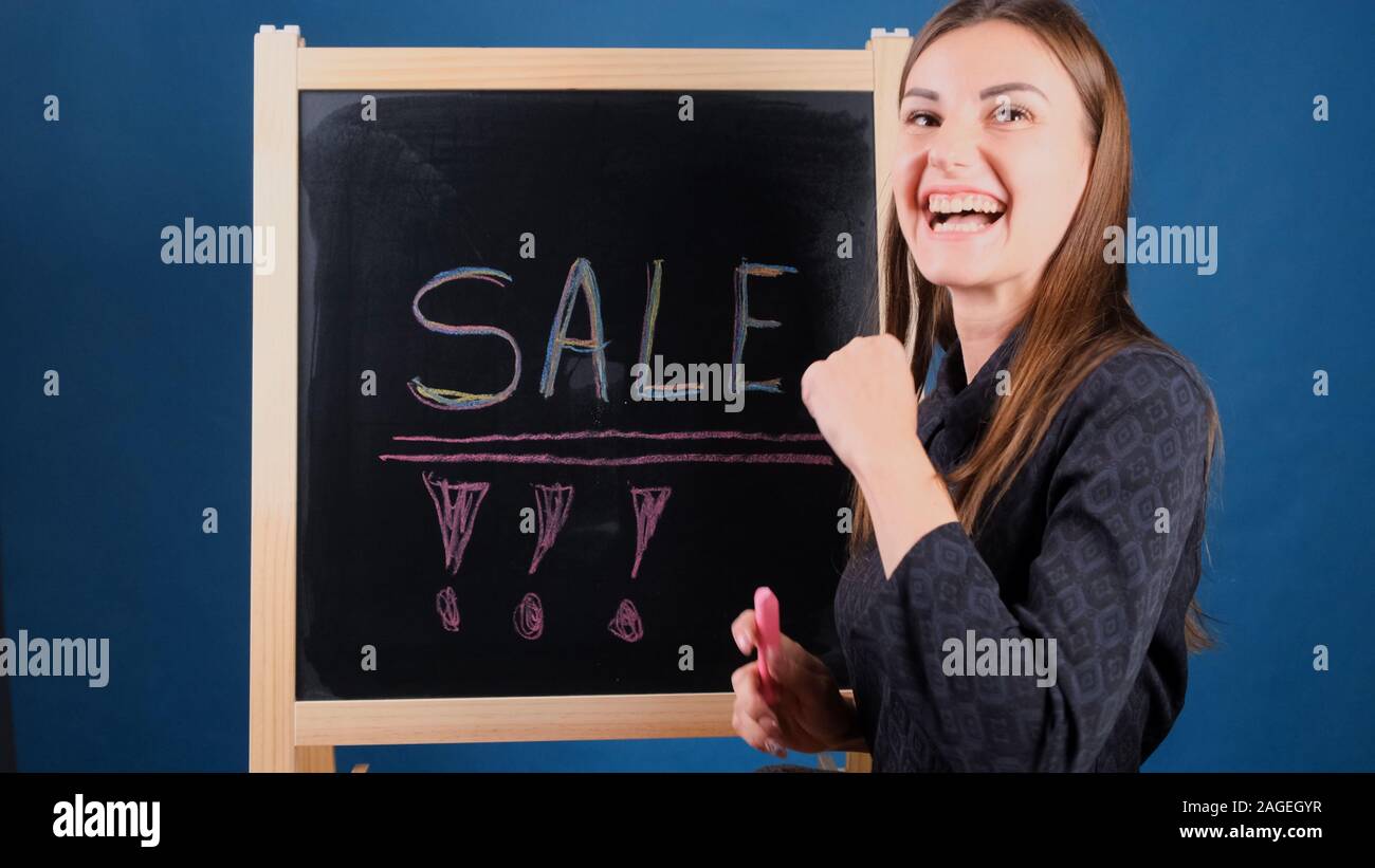 The inscription SALE is written on a blackboard. happy girl jumps ...