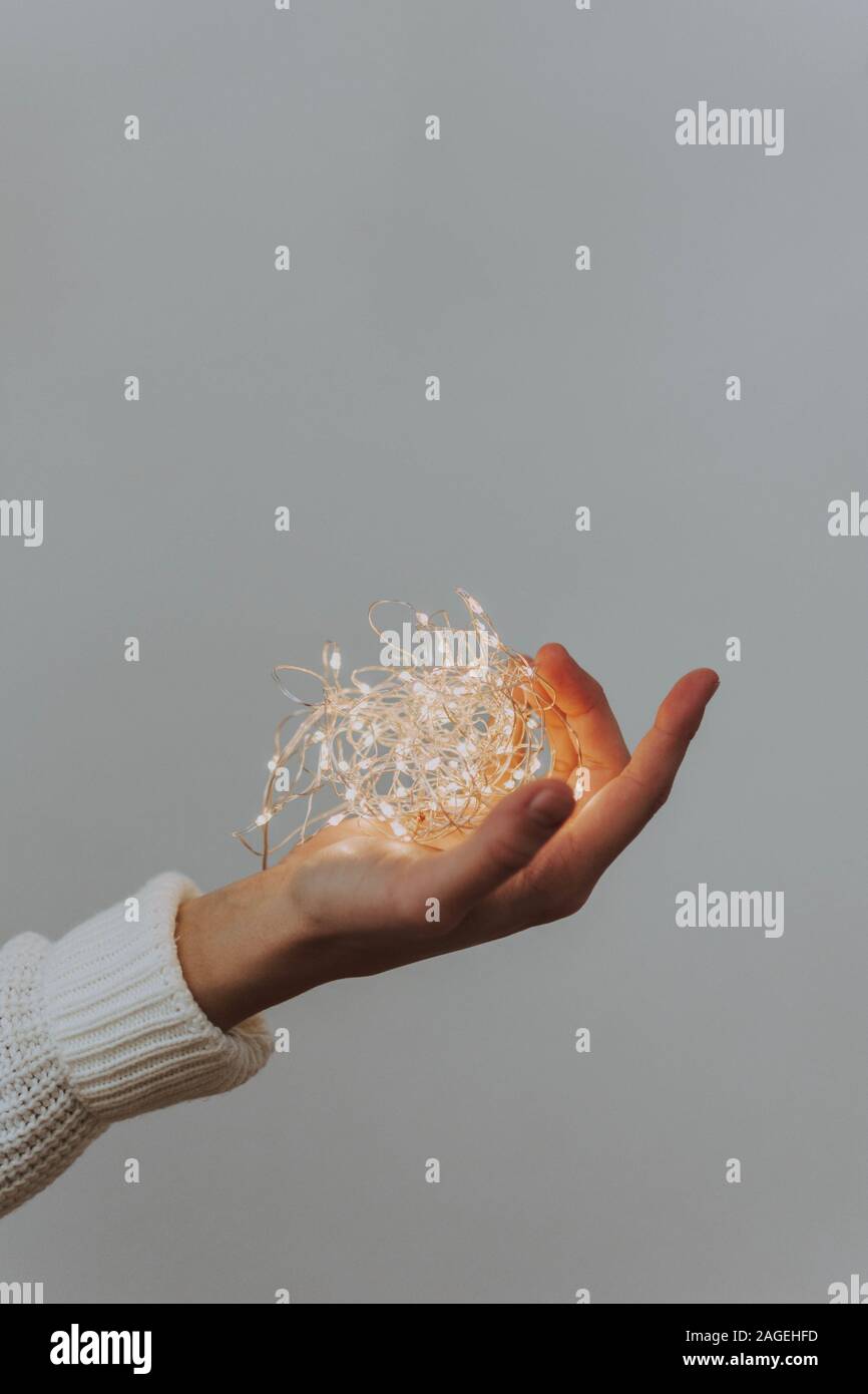 Vertical shot of a person holding a Christmas tree lights in its palm ...