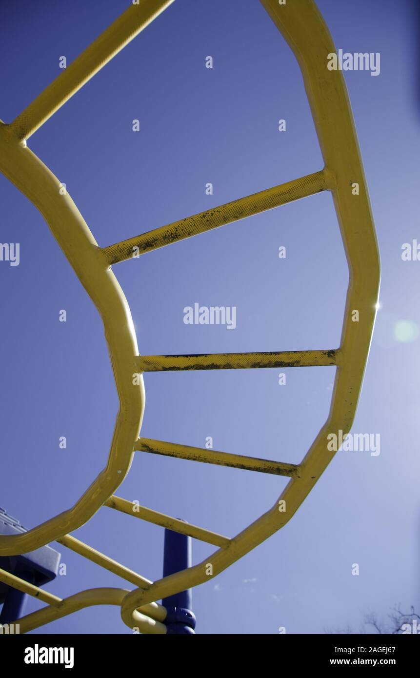 Low angle of a yellow playground equipment under sunlight and a blue ...