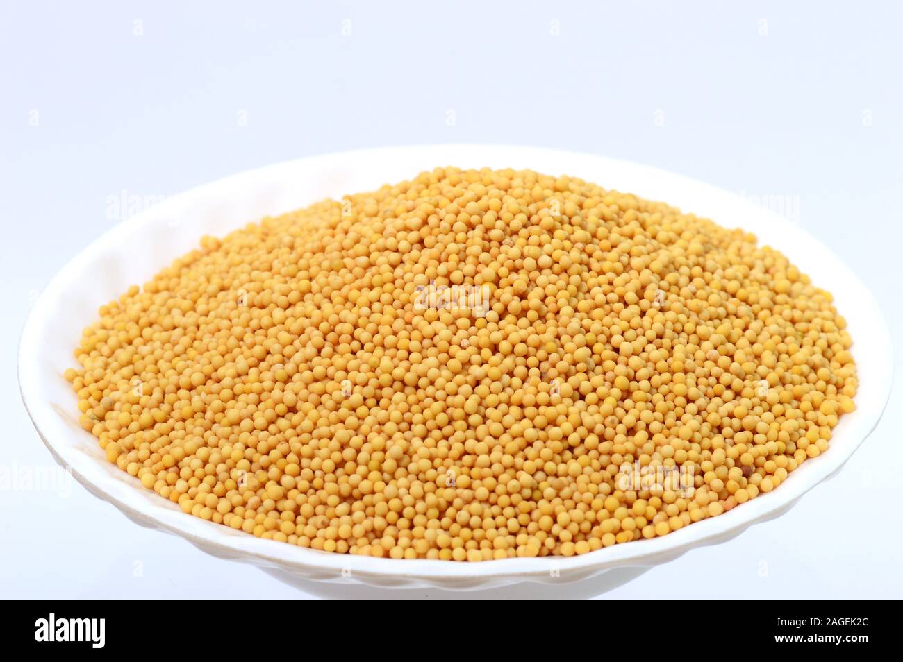 yellow mustard seeds in plate isolated on white background Stock Photo ...