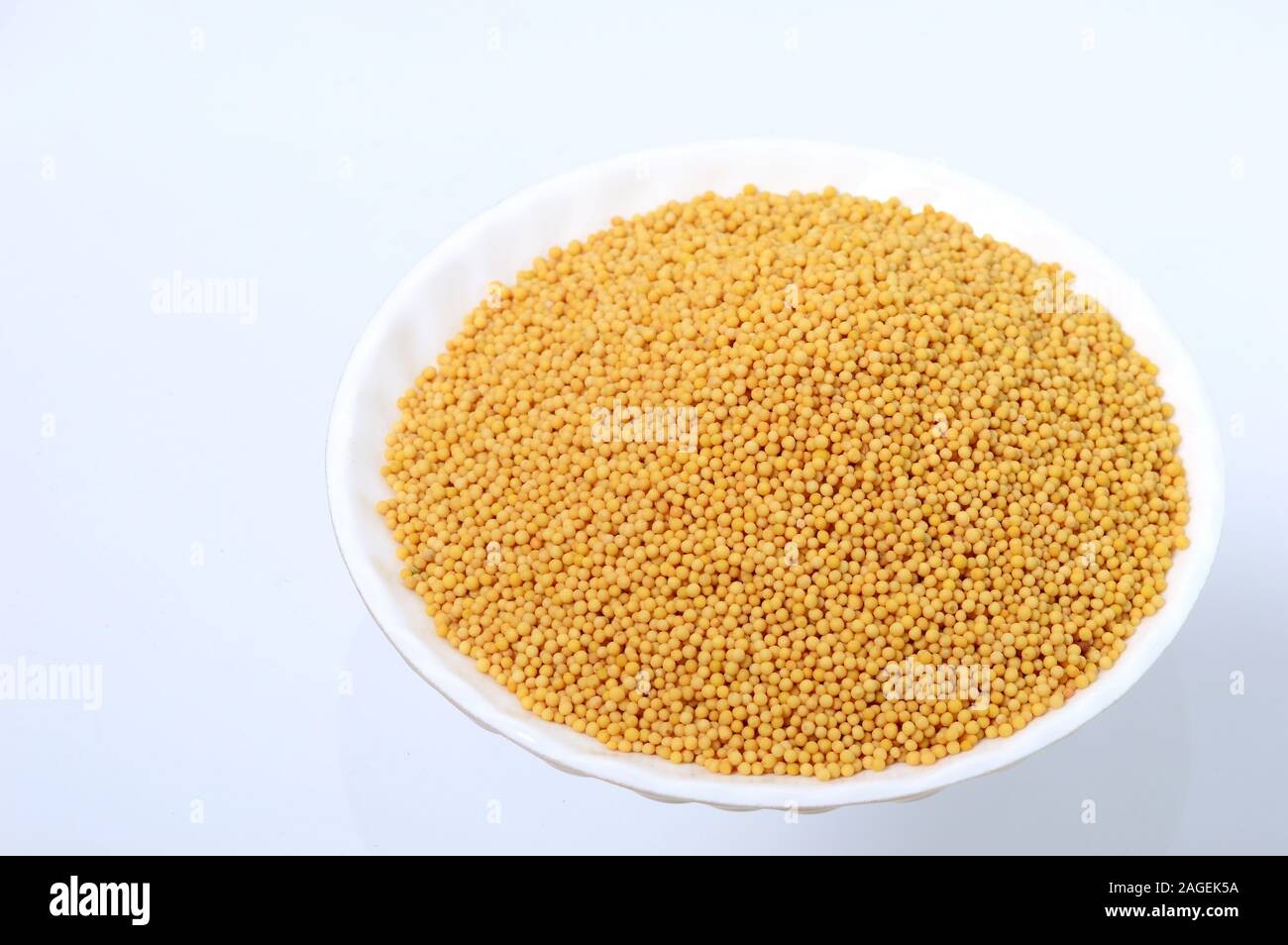 yellow mustard seeds in plate isolated on white background Stock Photo ...