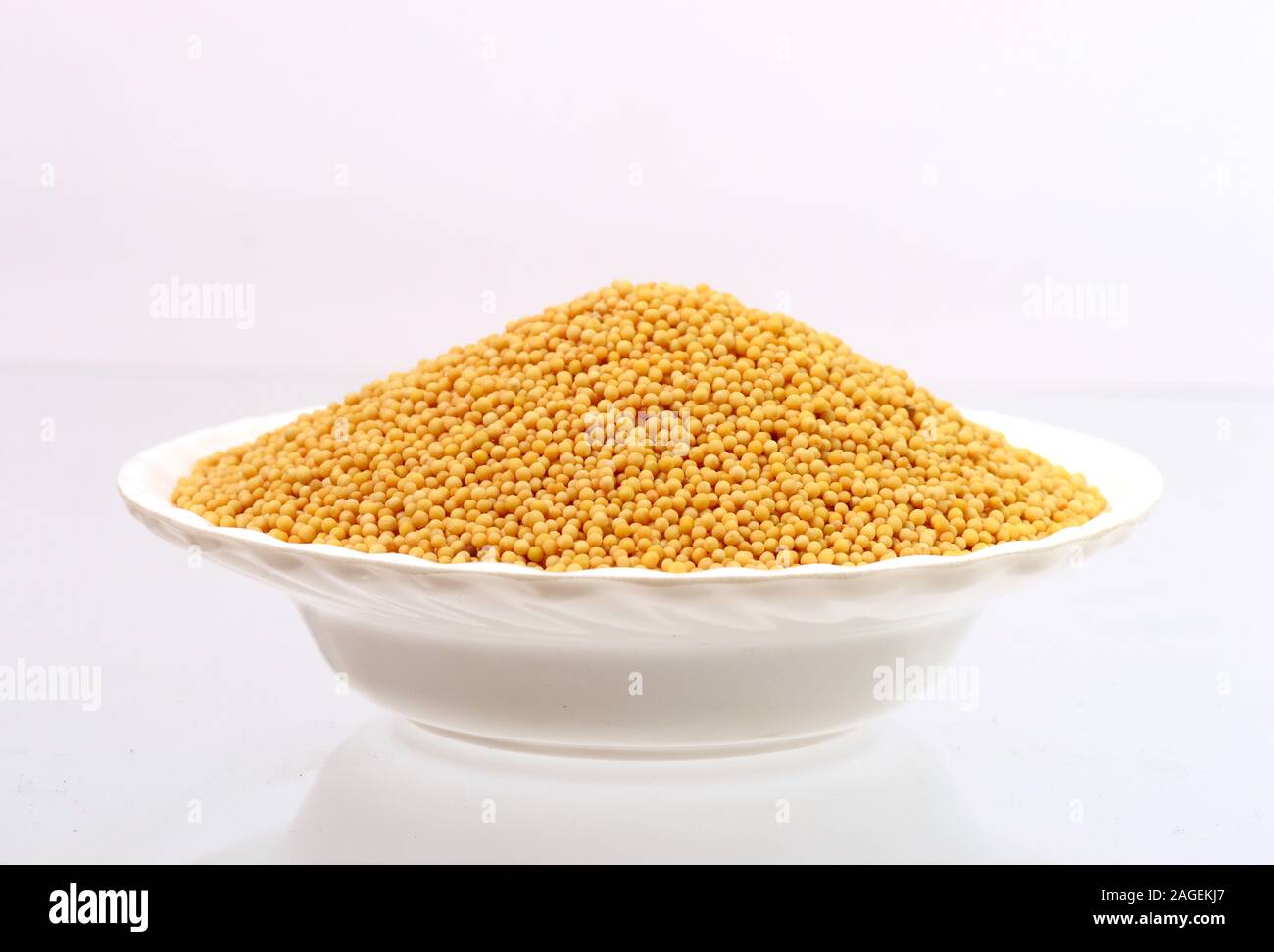 yellow mustard seeds in plate isolated on white background Stock Photo ...
