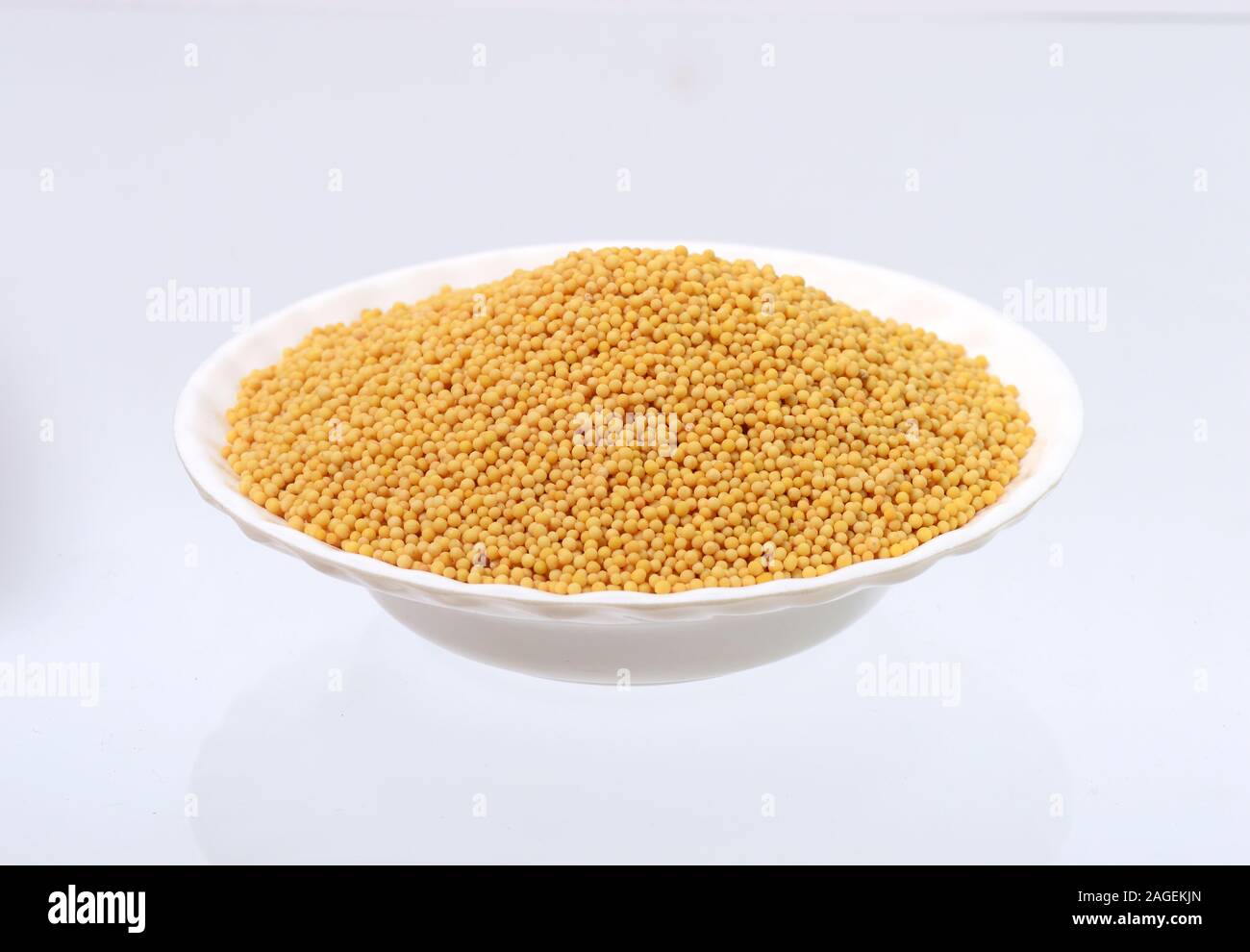 yellow mustard seeds in plate isolated on white background Stock Photo ...