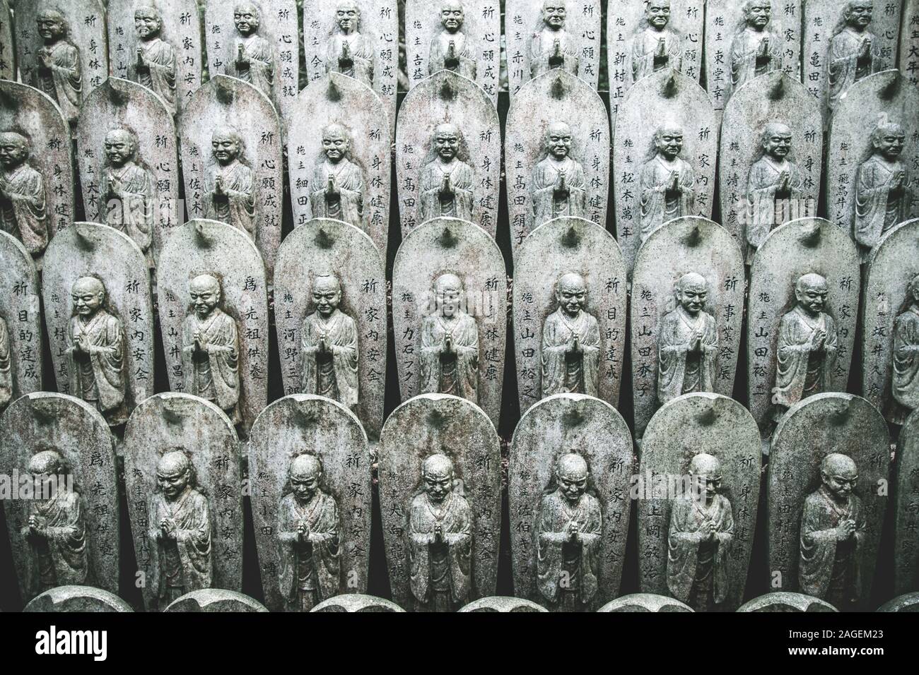 Row of Buddhist Jizo statues in a temple in Japan with hieroglyphs on ...