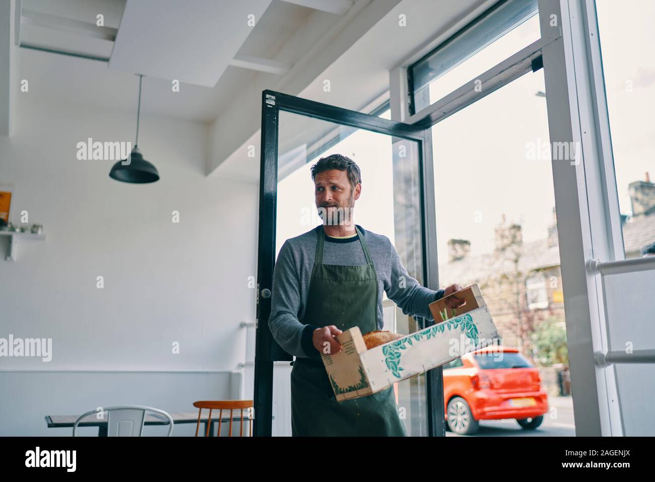 Man carrying crate of food supply into restaurant Stock Photo - Alamy