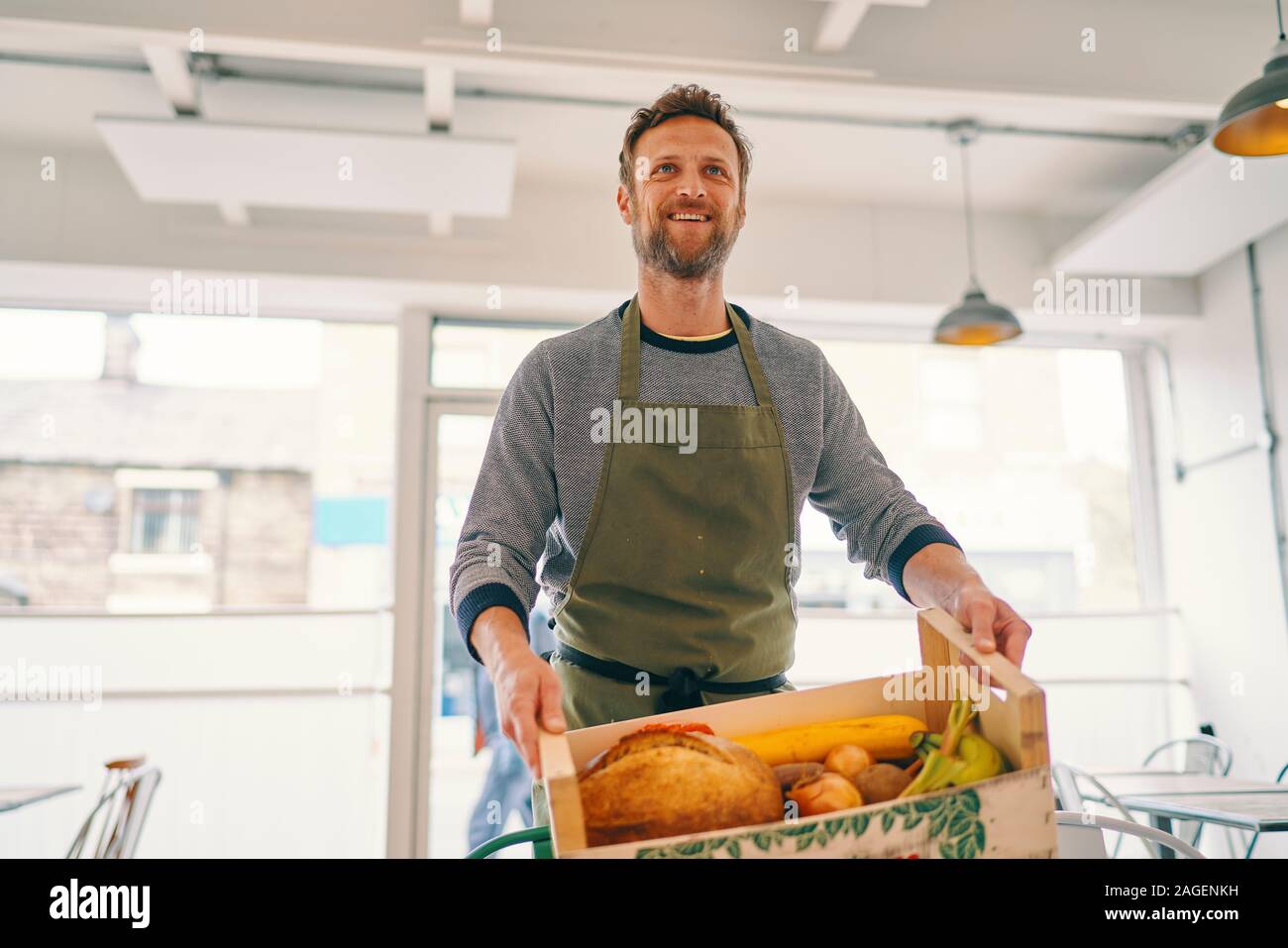 Man carrying crate of food supply into restaurant Stock Photo - Alamy