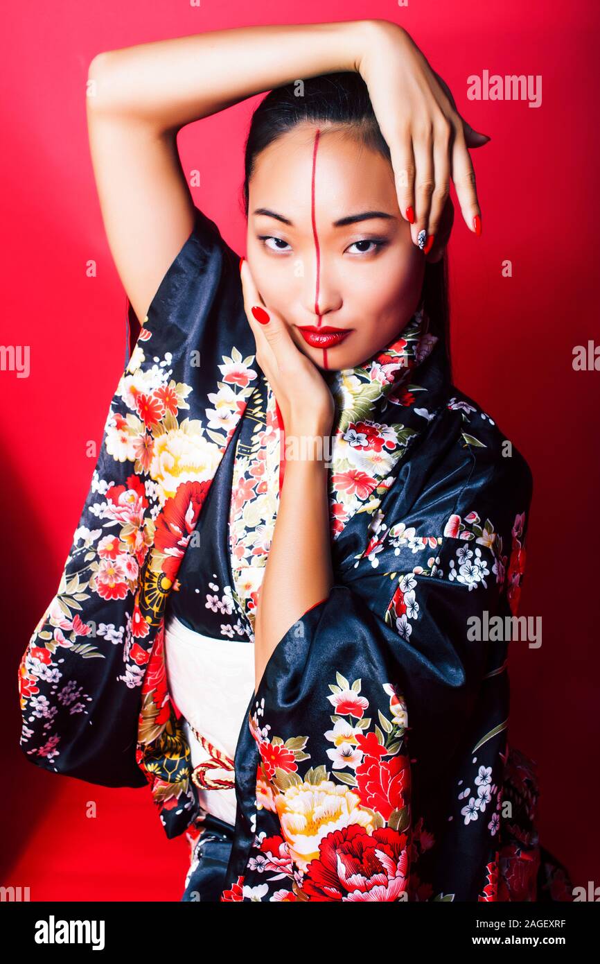 young pretty geisha on red background posing in kimono, oriental ...