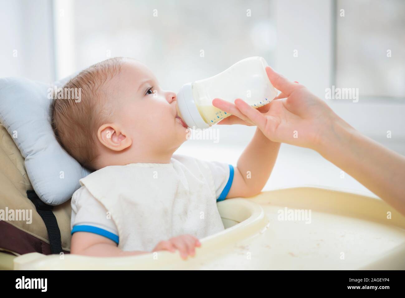 woman gives to drink baby milk in the house Stock Photo - Alamy