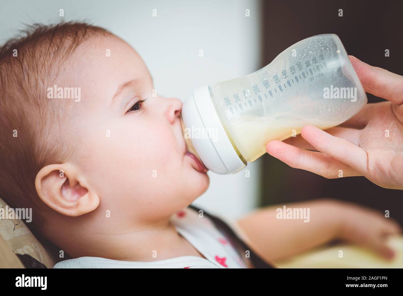 woman gives to drink baby milk in the house Stock Photo - Alamy