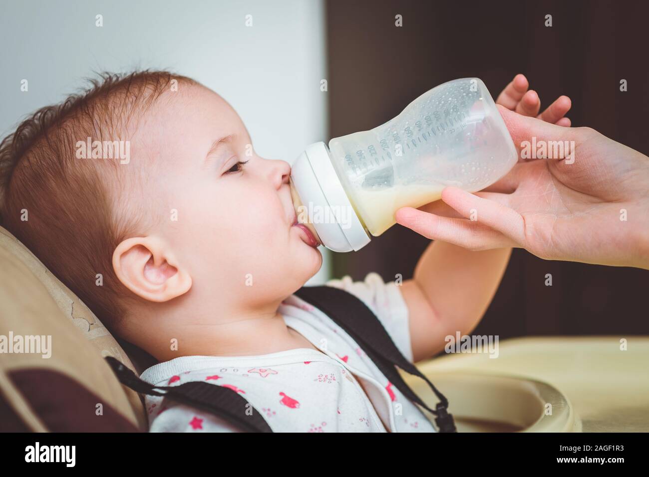 woman gives to drink baby milk in the house Stock Photo - Alamy