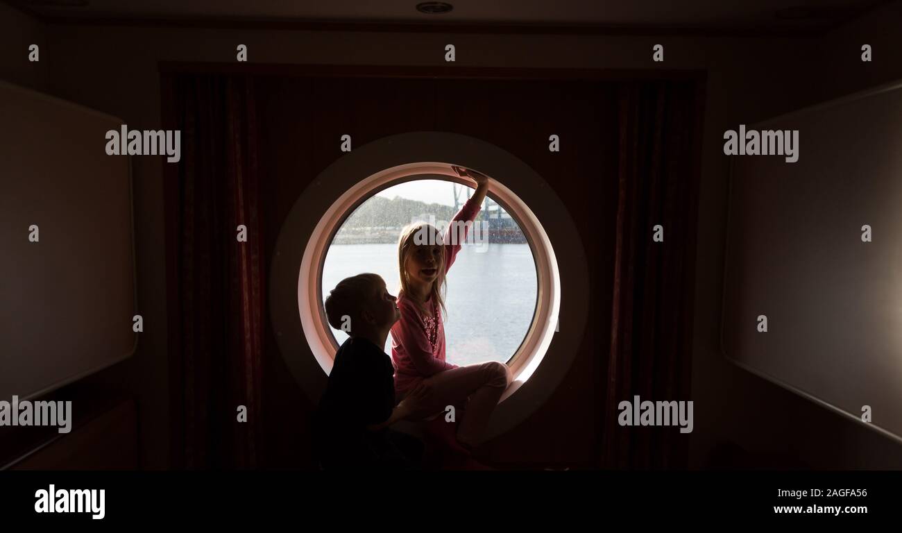 Kids sitting at a round window in a cruise ship cabin Stock Photo - Alamy