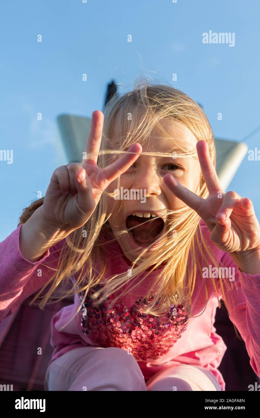 Young girl showing a victory sign smiling Stock Photo - Alamy