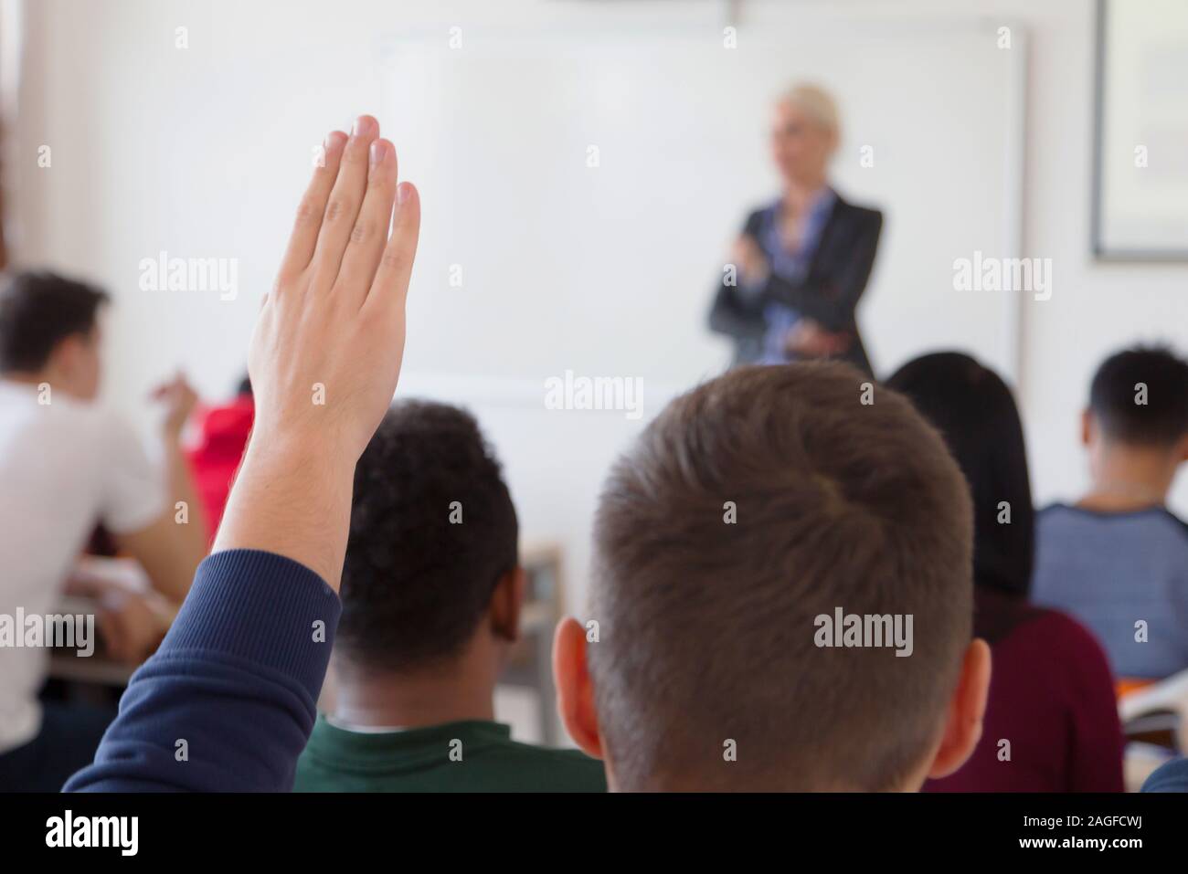 Group of university students sitting at classroom and holding hand up ...