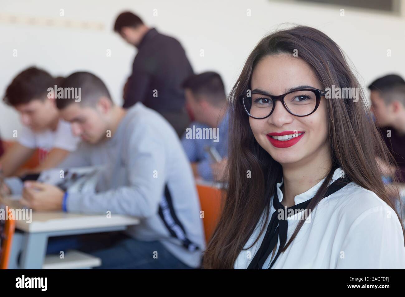 Attractive wearing glasses female student smiling into camera while ...
