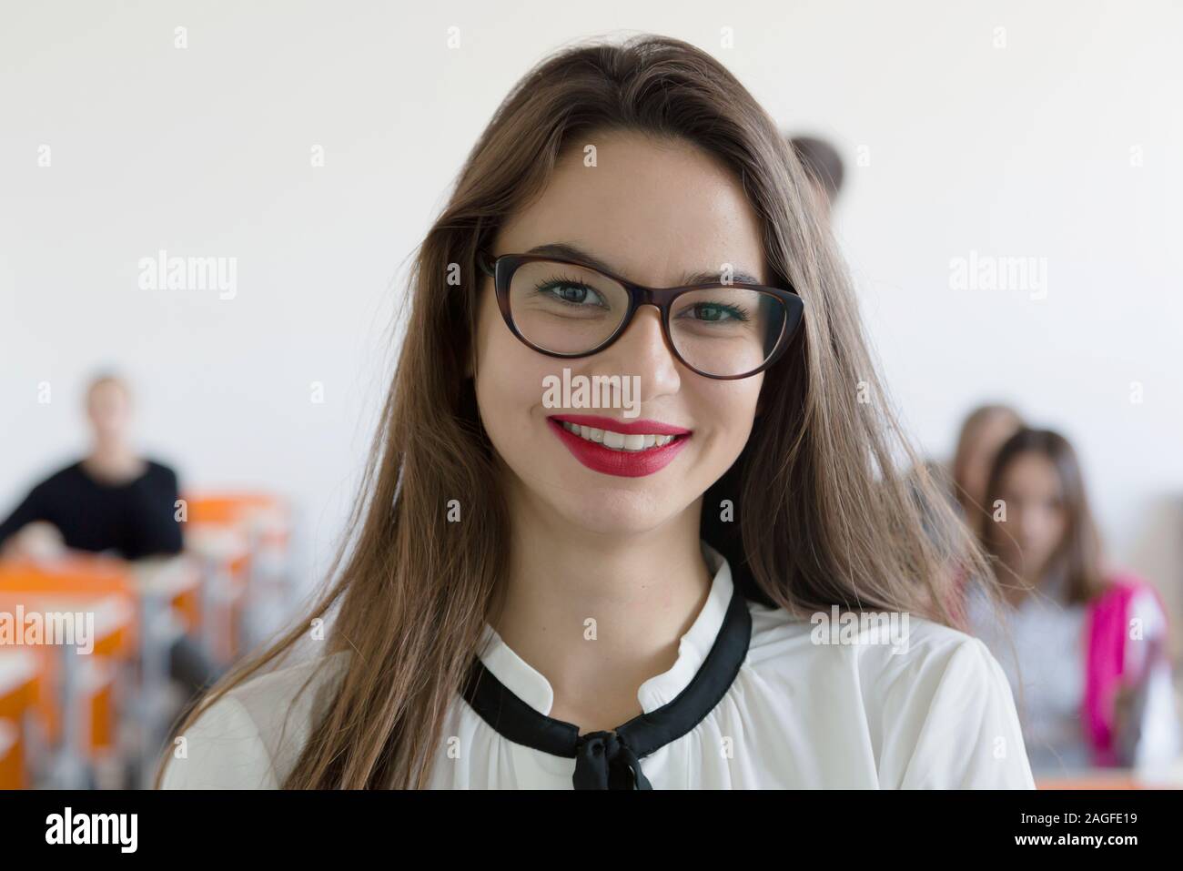 Attractive wearing glasses female student smiling into camera while ...