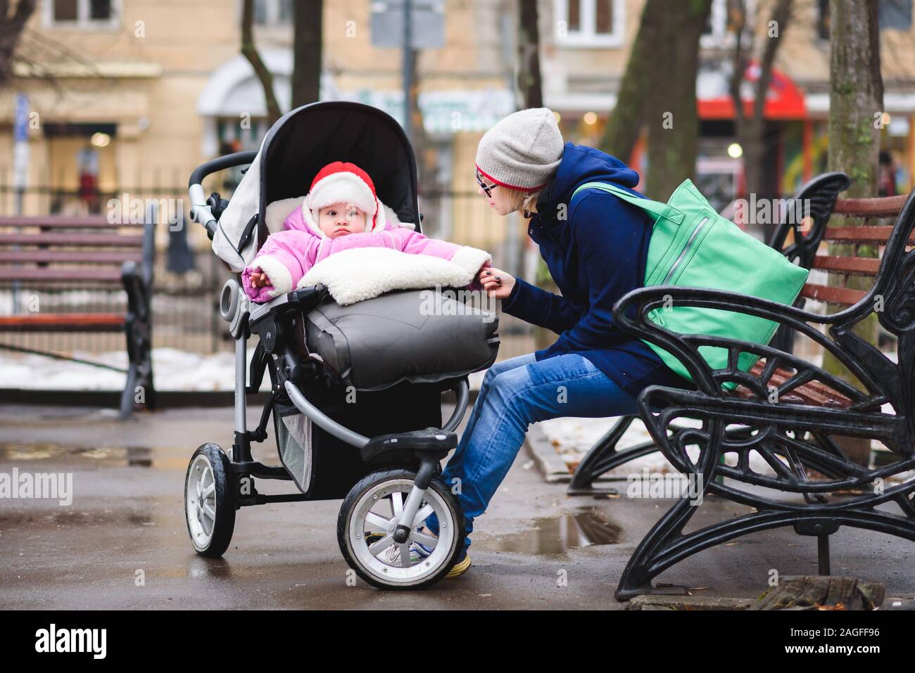 Mom sits on a bench next to a stroller Stock Photo - Alamy