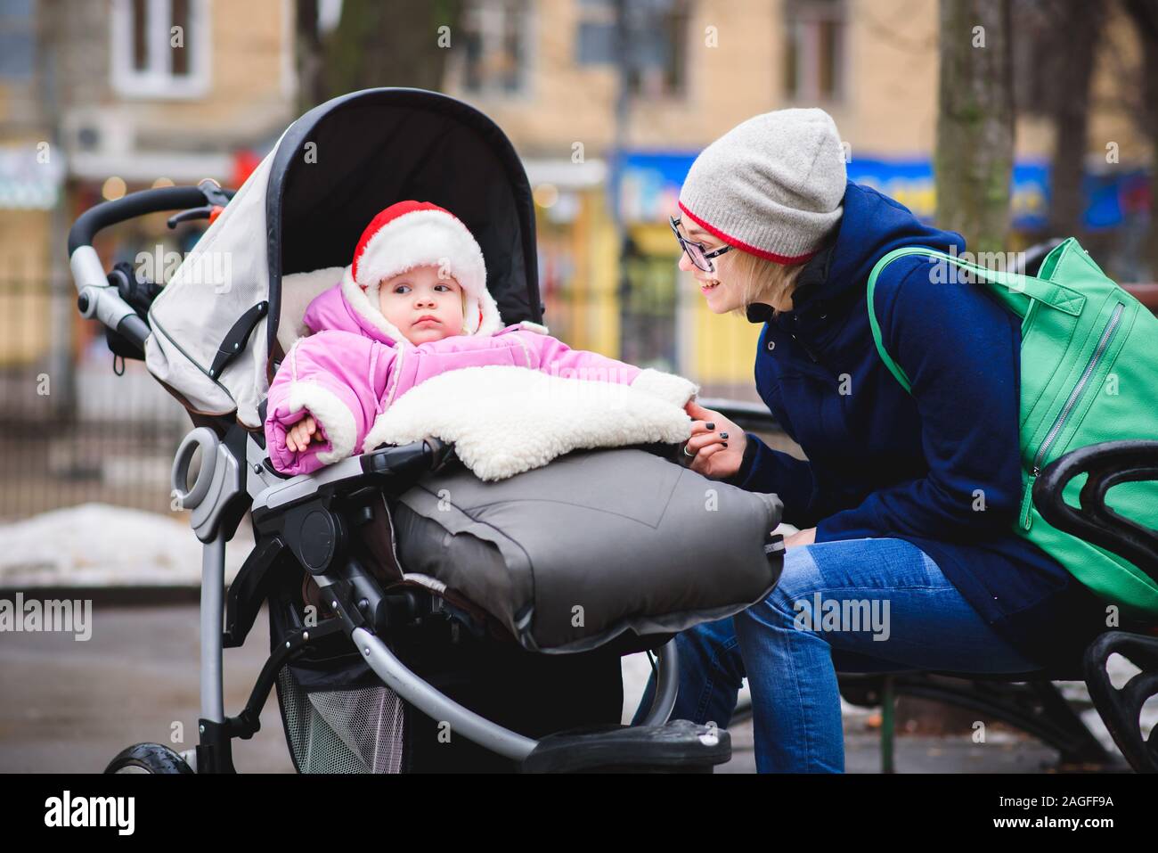 Mom sits on a bench next to a stroller Stock Photo - Alamy