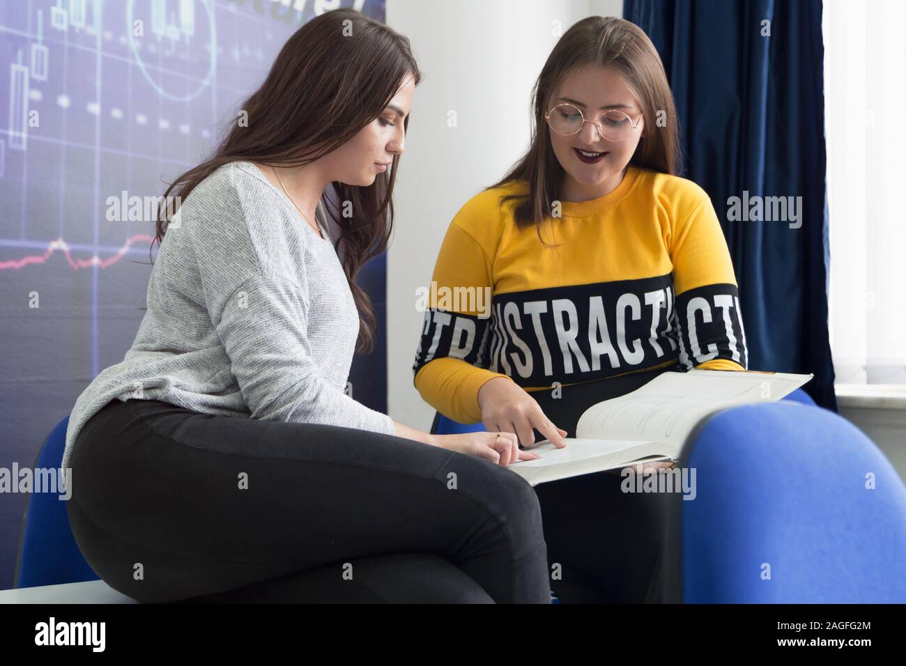 Campus life, students friendship.Two female students helping each other ...