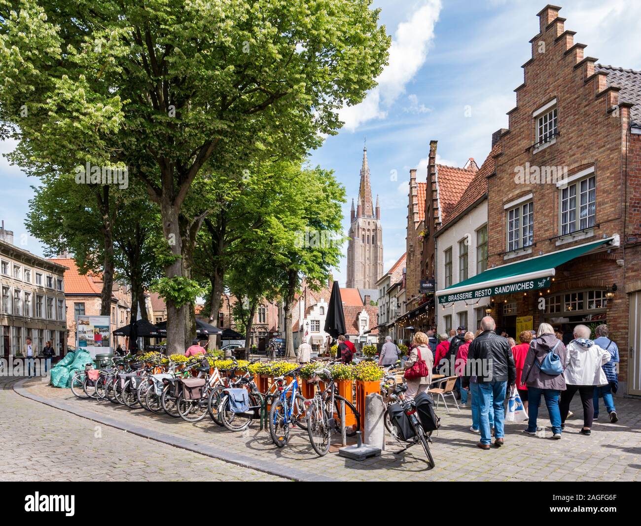 People, bicycles and restaurants on Walplein square in Bruges, Belgium ...