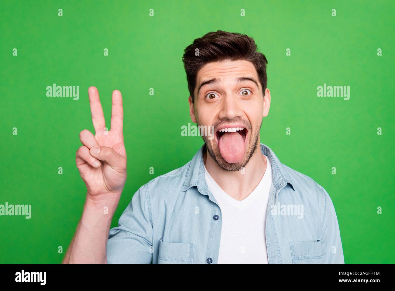 Closeup photo of amazing guy showing v-sign symbol sticking tongue out ...