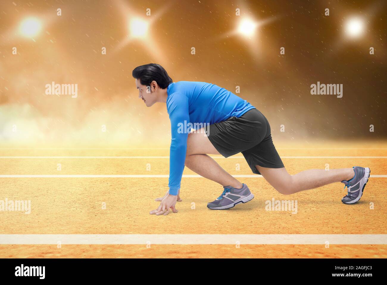 Asian runner man ready to run on the running track with spotlights ...