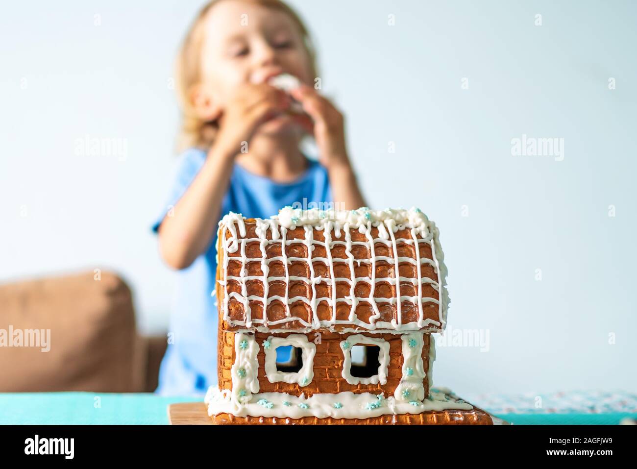 Cute little boy eats gingerbread house and having fun. Kid enjoy ...