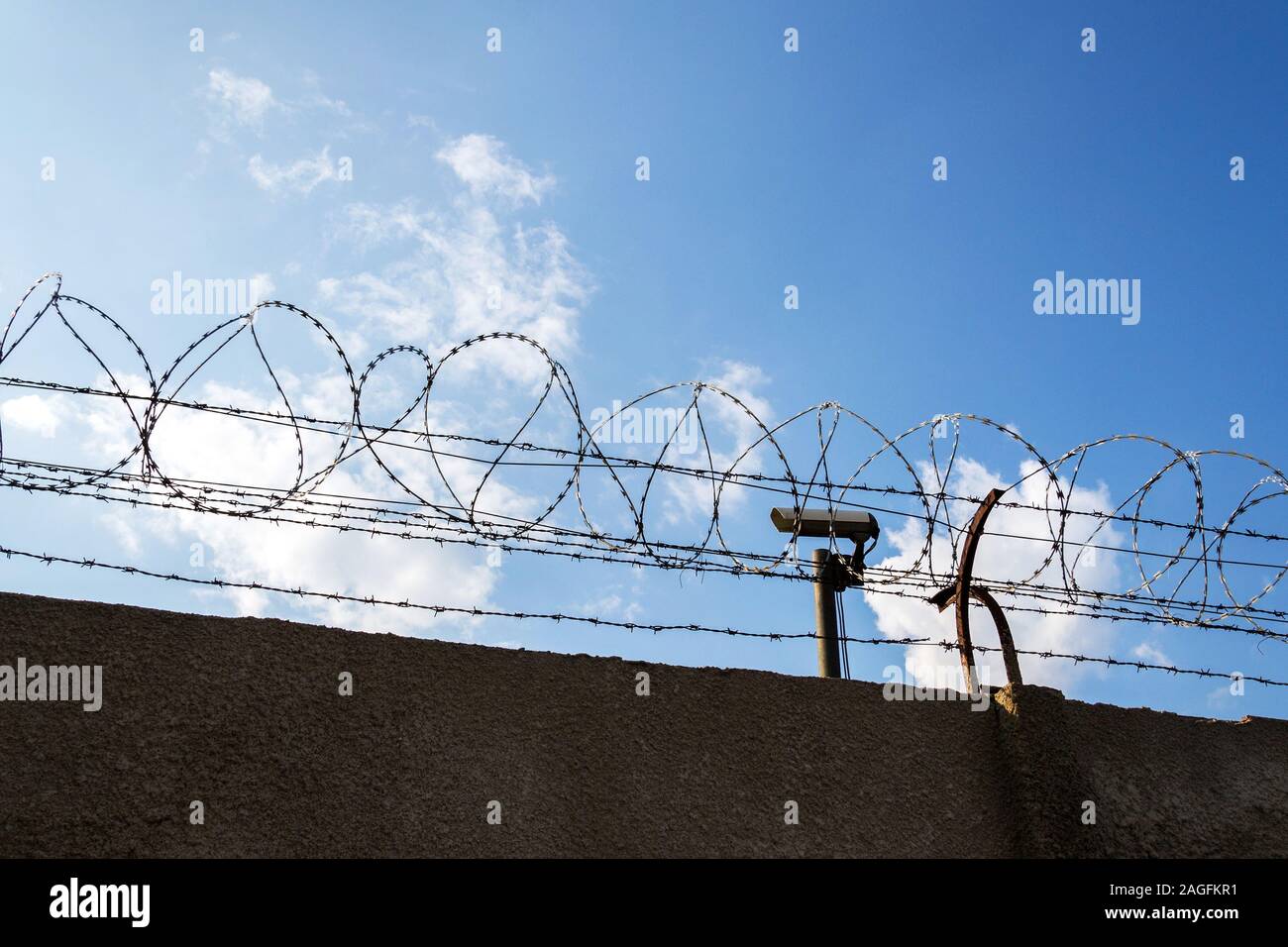 Security camera behind barbed wire fence on the wall, prison, security ...