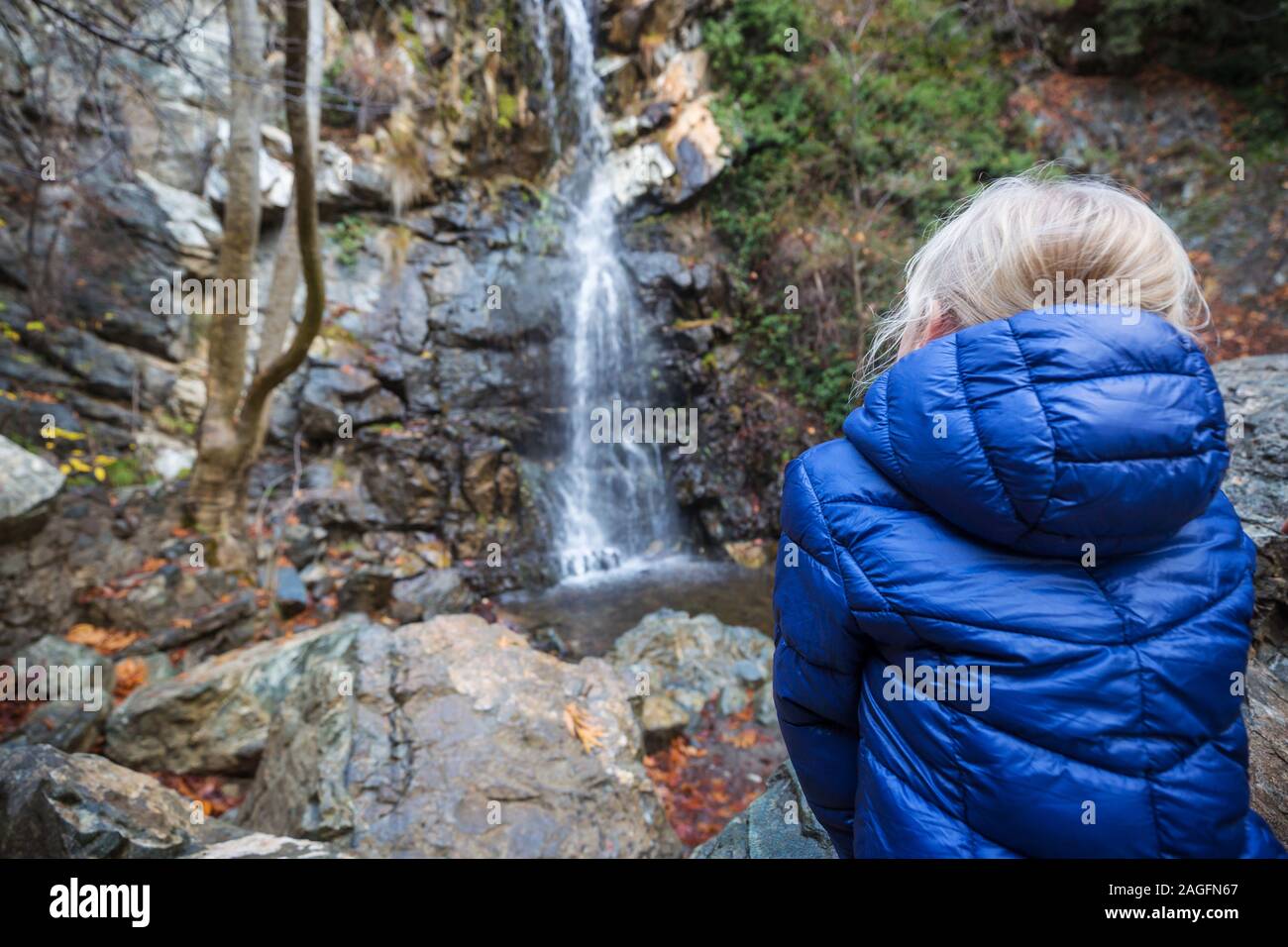 Little girl standing in front of waterfall Stock Photo - Alamy