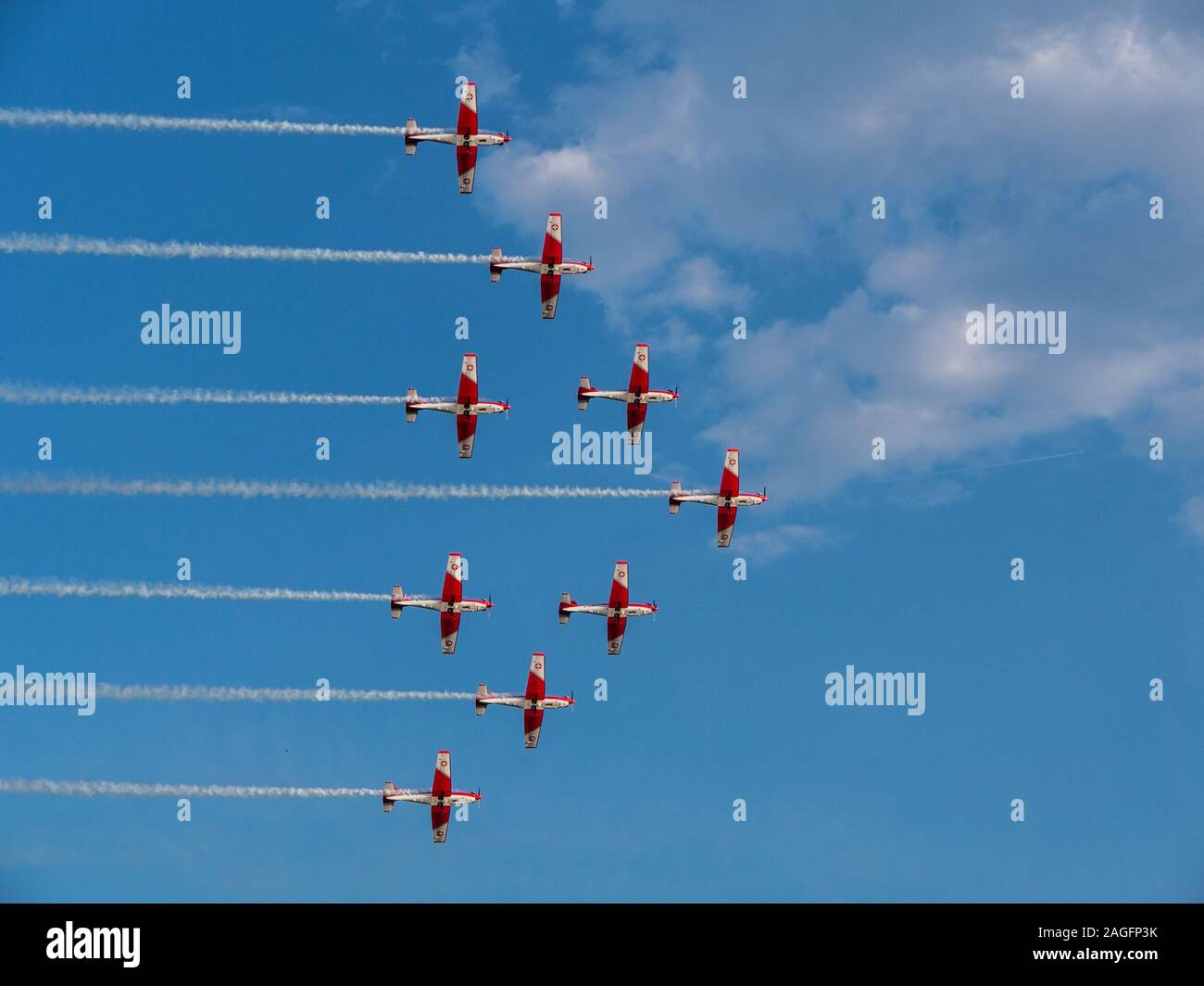 Red jets performing an airshow while leaving white tracks in the sky ...