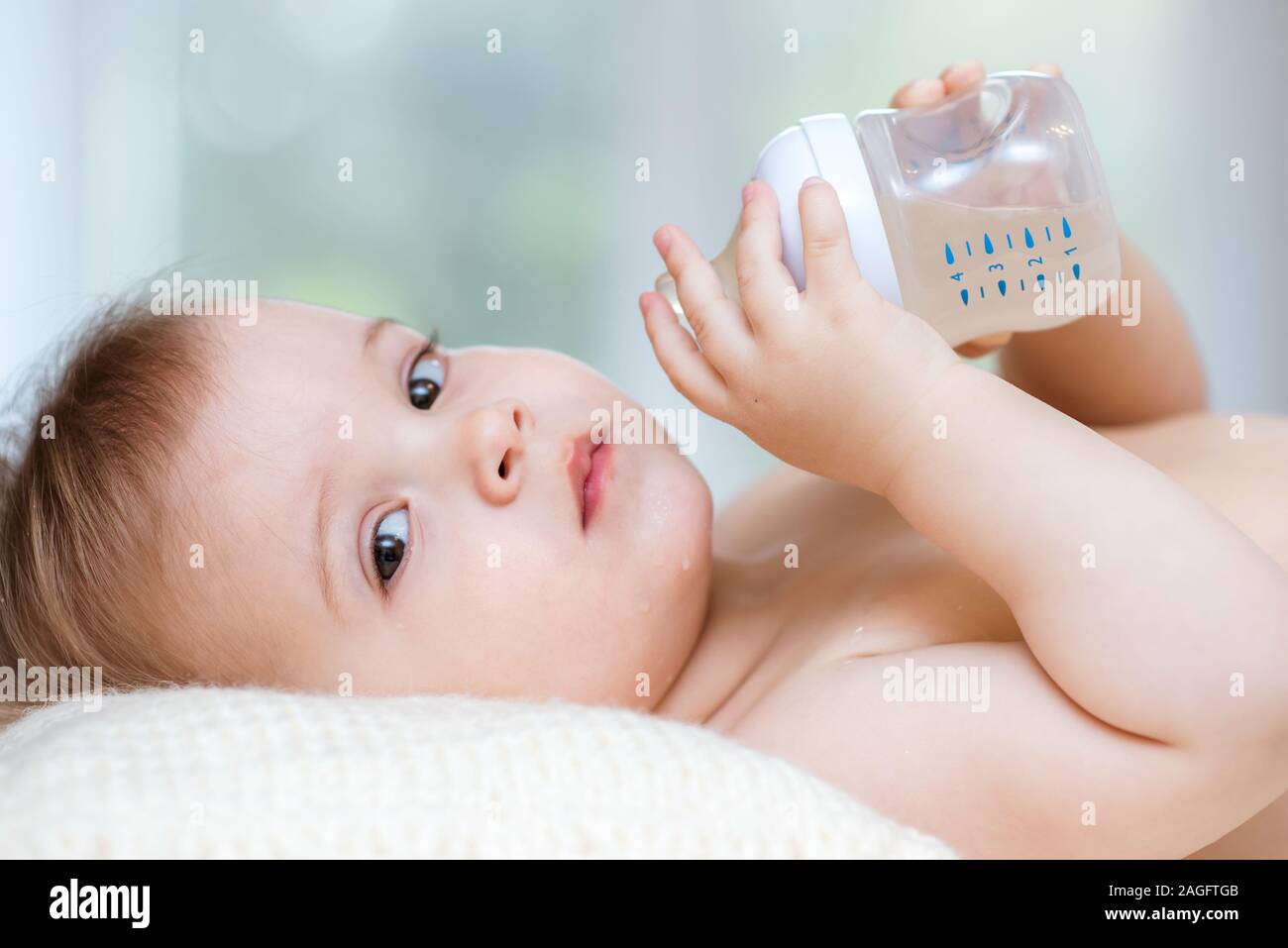 Baby drinks juice from a bottle at home Stock Photo - Alamy