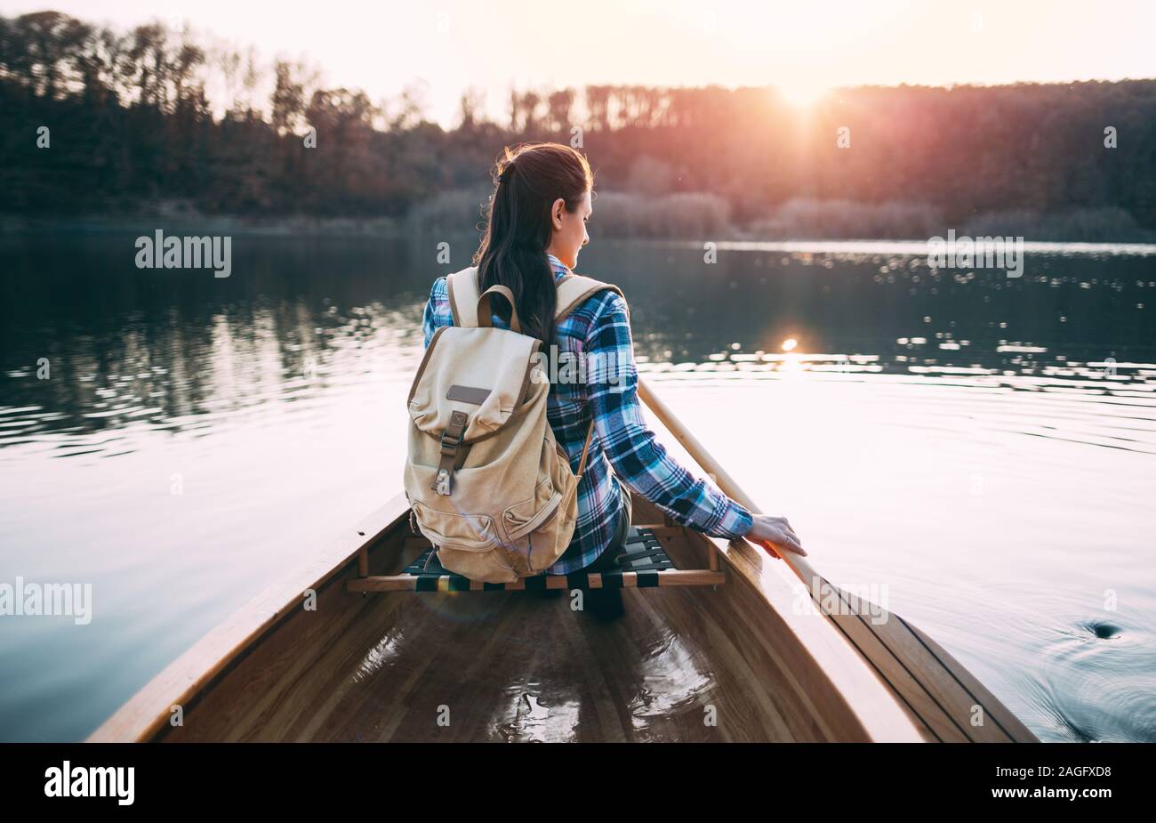 Rear view of woman canoeing on the sunset lake Stock Photo - Alamy