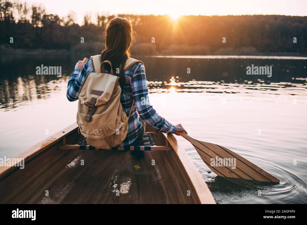 Rear view of woman canoeing on the sunset lake Stock Photo - Alamy