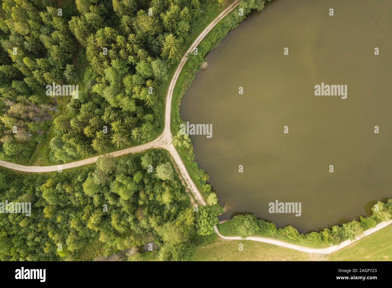 Top view of hiking path through forest next to a lake shore in summer ...