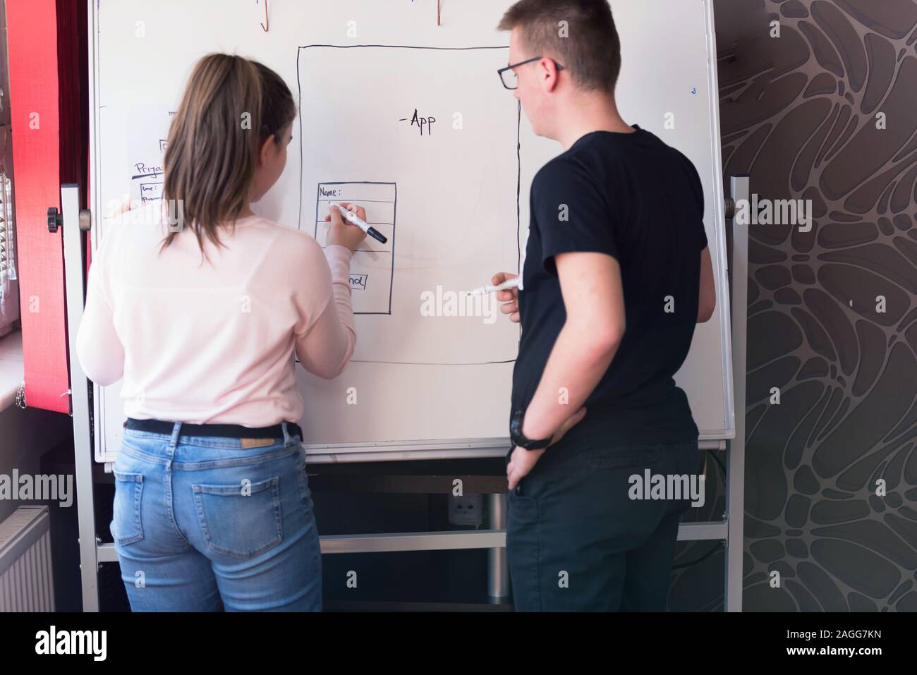 Two young college students writing on the chalkboard/blackboard during ...