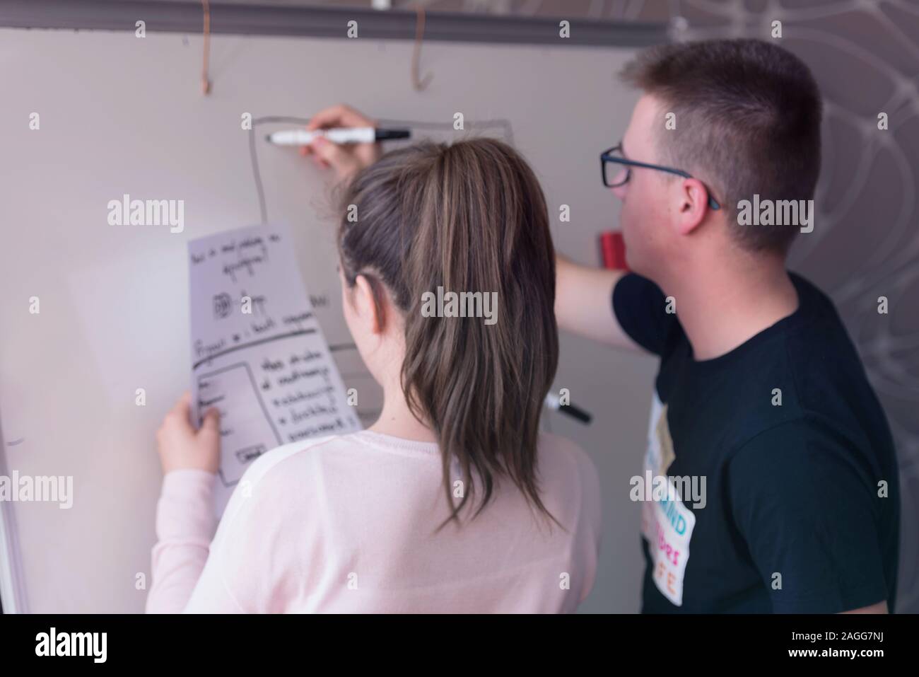 Two young college students writing on the chalkboard/blackboard during ...
