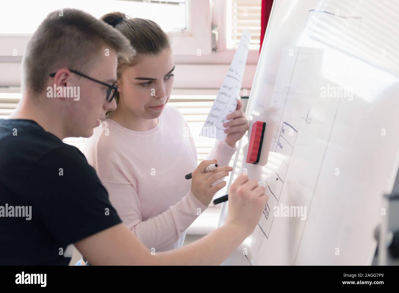 Two young college students writing on the chalkboard/blackboard during ...