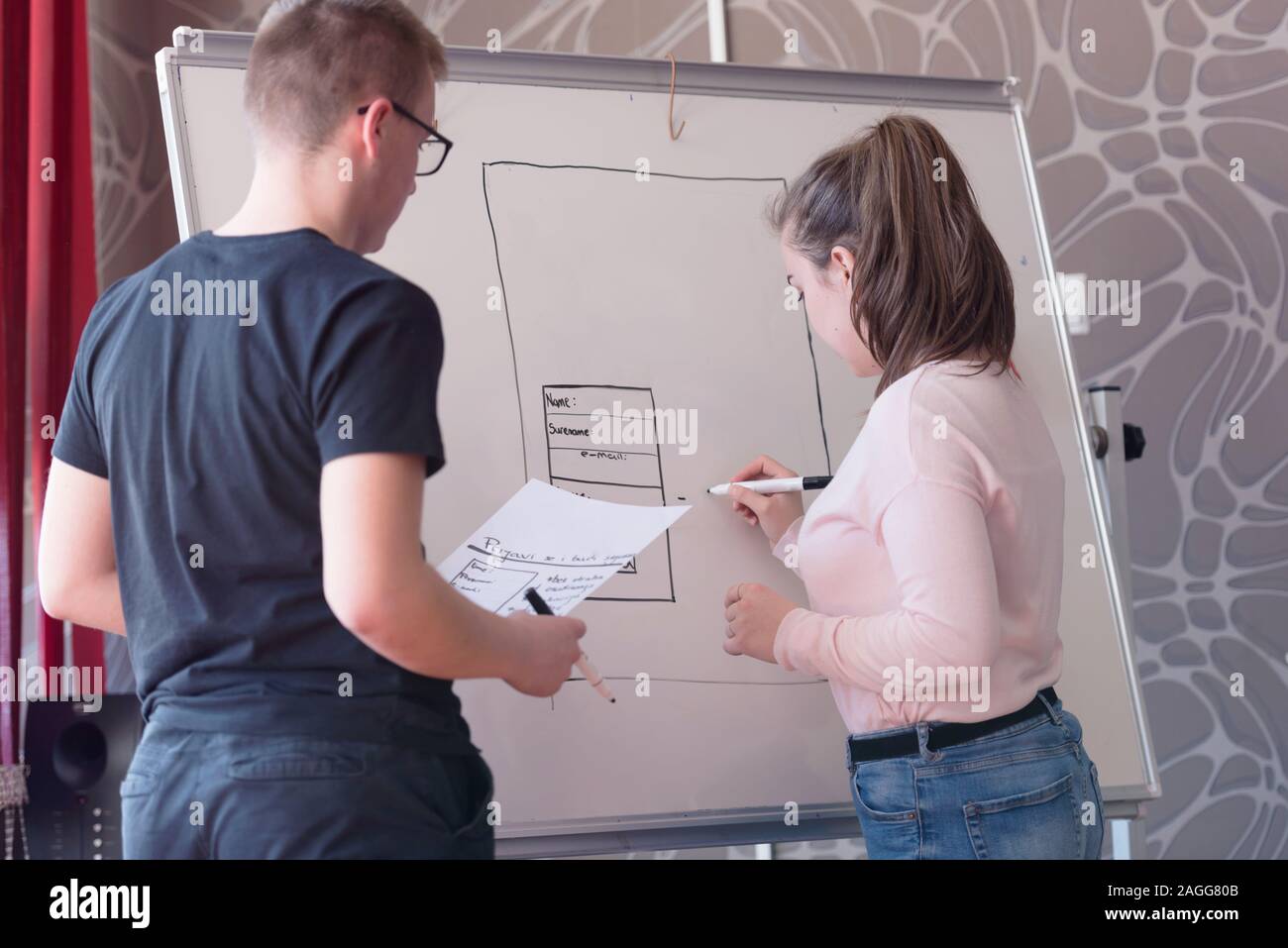 Two young college students writing on the chalkboard/blackboard during ...