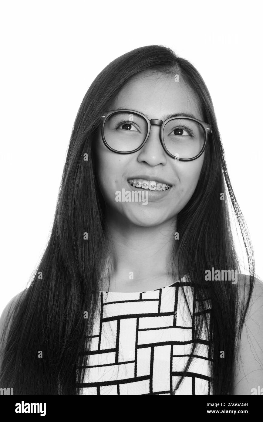 Face of young happy Asian teenage nerd girl smiling while thinking ...