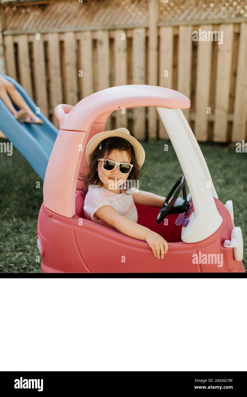 Toddler riding toy car in backyard Stock Photo - Alamy