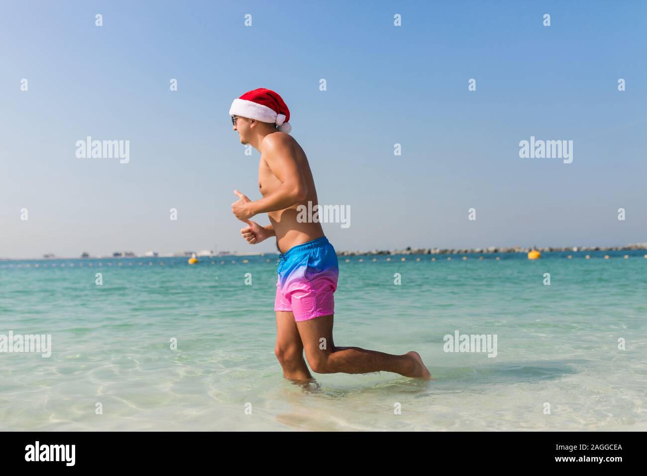 Young man in santa hat running in sea water Stock Photo - Alamy